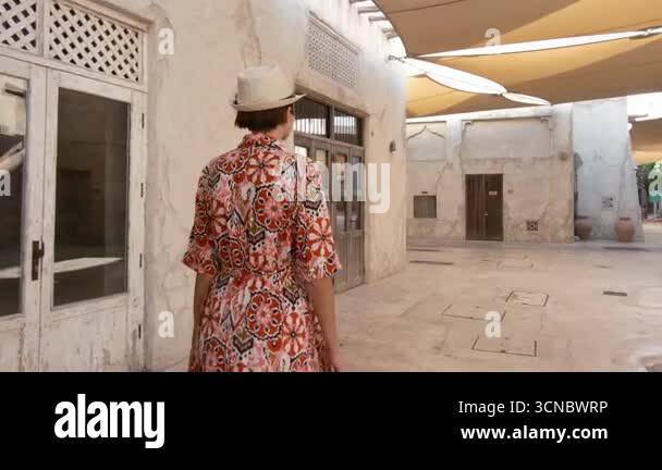 Young woman in ethnic dress and hat exploring Al Seef Park in Dubai ...