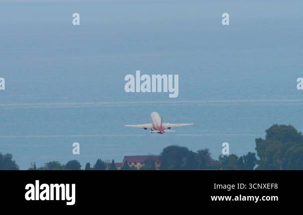 Distant rear view of a jet airliner ascending into the sky after ...