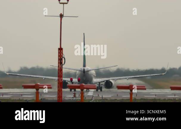 Rear view of jet aircraft on runway. Airliner gaining speed for takeoff ...