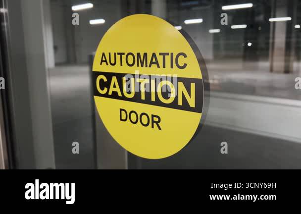 Close-up of a yellow circular caution sign with text on a glass ...