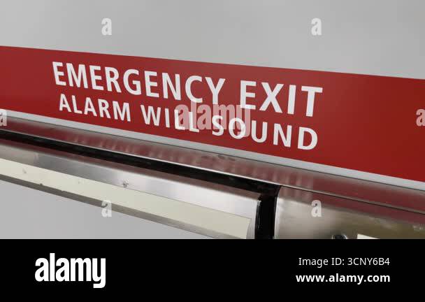 Close-up of a red sign with white text Emergency Exit Alarm will sound ...