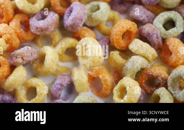 A bowl filled with vibrant cereal rings floating in milk during ...