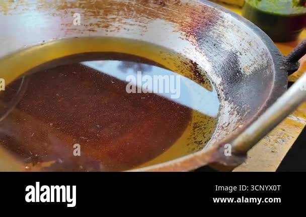 A frying pan filled with oil reflects sunlight and captures vibrant ...