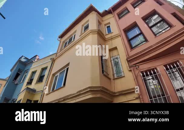Buildings in shades of yellow and pink line a lively street under a ...