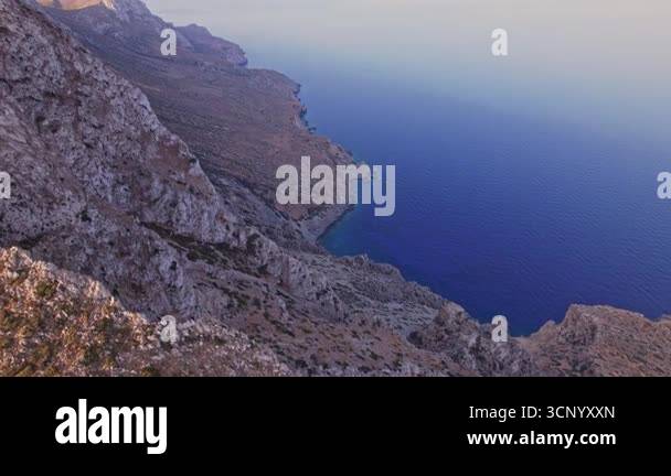 The coastline features steep rocky cliffs plunging into the deep blue ...