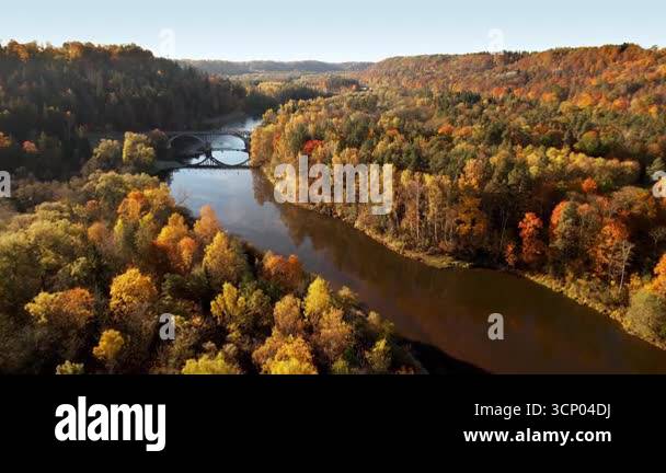 Bright autumn colors surround a serene river as it flows beneath a ...