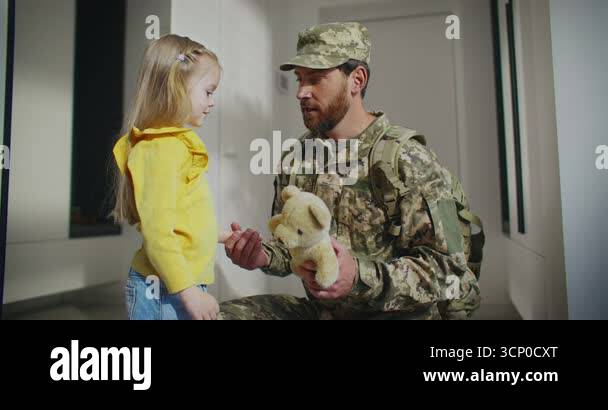 Brave soldier standing at exit of house and clutching daughters small ...