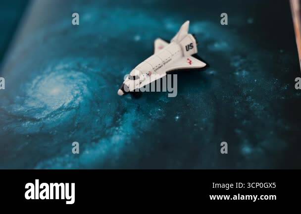 Close up of a miniature toy space shuttle placed on a blue cosmic ...
