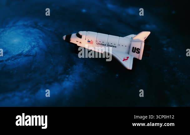 Close up of a miniature toy space shuttle placed on a blue cosmic ...