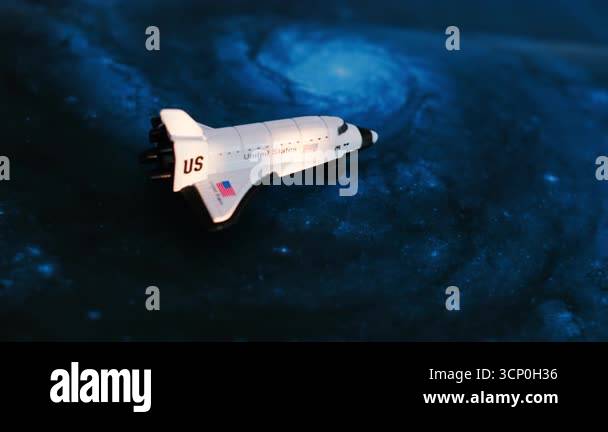 Close up of a miniature toy space shuttle placed on a blue cosmic ...