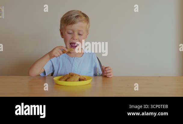 Happy child eating fast food at home chicken nuggets. Boy eats food at ...