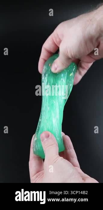Close-up of hands squeezing green slime with squishy texture and ...