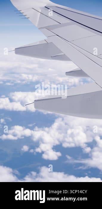 Bright window seat view of an airliner wing cruising above a sea of ...