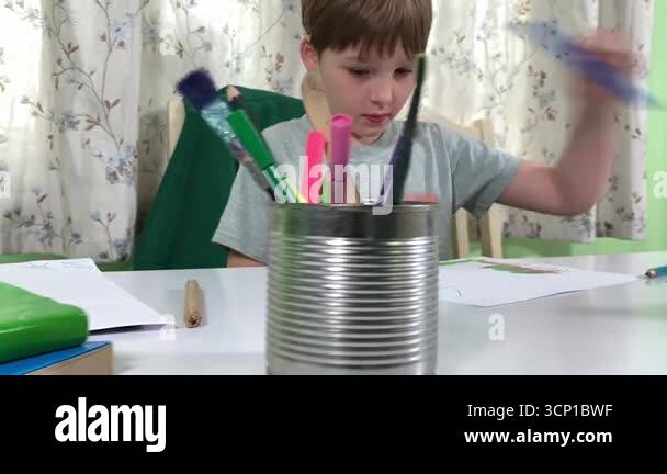 Adorable school-age boy drawing with pencils at home, fully engaged in ...