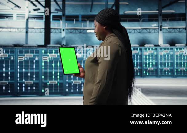 Software developer at work using green screen tablet in data center to ...