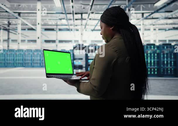 Technician with green screen laptop in data center implementing advanced power management ...