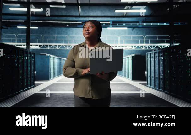 Admin walks between server farm rows, using laptop to upgrade rigs for ...