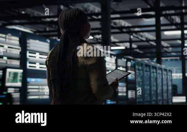 Data center system administrator monitors data center metrics on tablet ...
