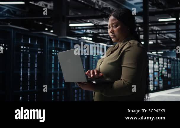 Software developer in data center using laptop to upgrade systems for ...