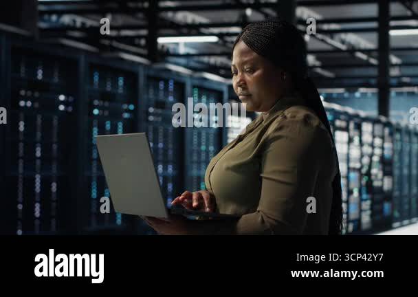 Software developer in data center using laptop to upgrade systems for ...