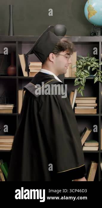 Graduate dressed in black robe and cap proudly and happily holds ...