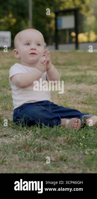 Baby engages with grass and leaves, exploring textures and colors in a ...
