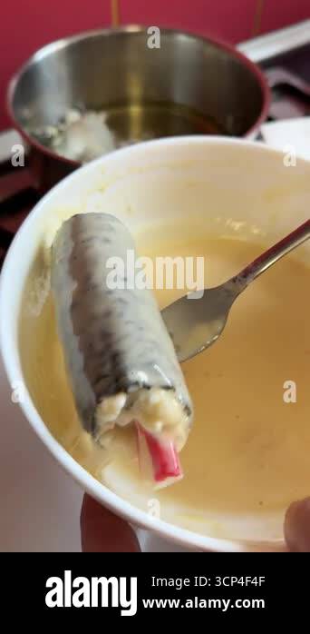 A person frying spring rolls in hot oil using a frying pan on a gas ...