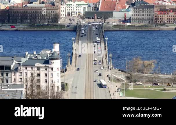 A busy bridge spans a wide river in a European city, with cars, trams ...