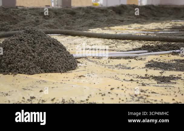 Workers spread and level liquid foam concrete screed over a yellow ...