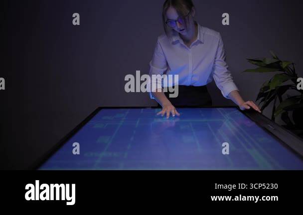 Behind a large monitor instead of a desk, a woman actively uses an ...