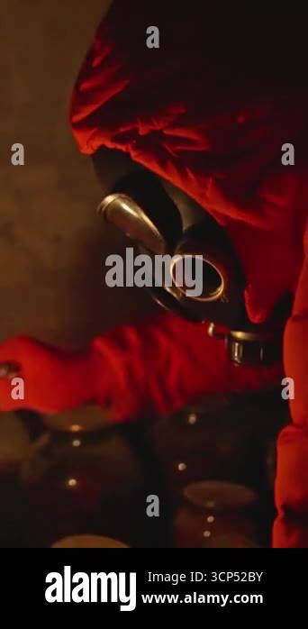 A person in gas mask, in basement, lights candle. A shadowy figure ...