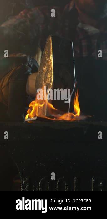 Close-up of blacksmith forging glowing hot iron on anvil with flying ...