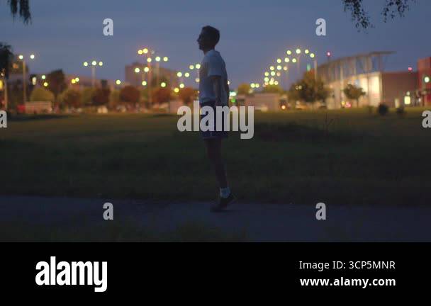 A dedicated runner exercises in a scenic city park at twilight, jogging ...