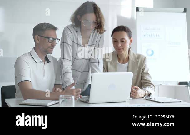 Professional team working together, reviewing data on laptop screen ...