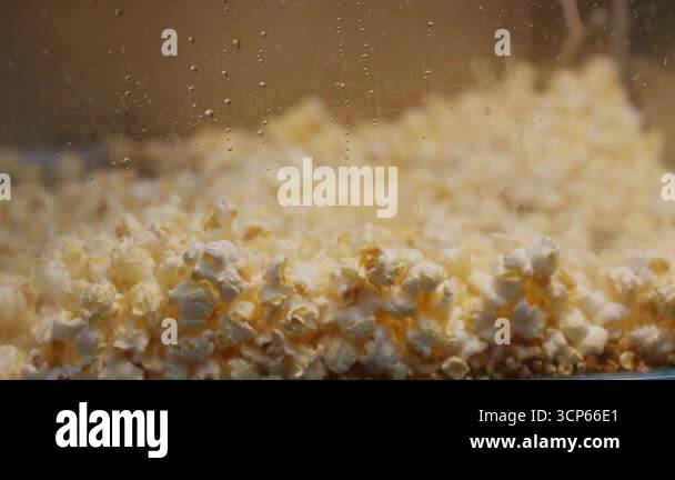 Close-up of freshly popped popcorn inside machine with metal scoop ...