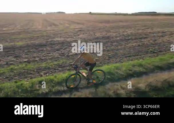 Man wearing helmet and sportswear riding gravel bike on dirt road ...