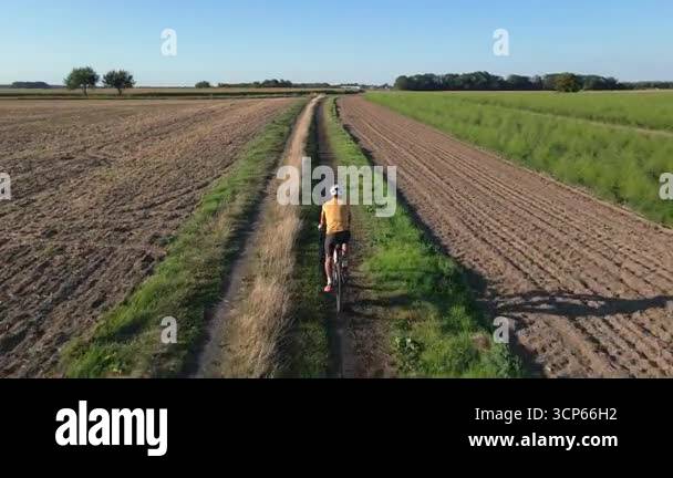 Man wearing helmet and sportswear riding gravel bike on dirt road ...