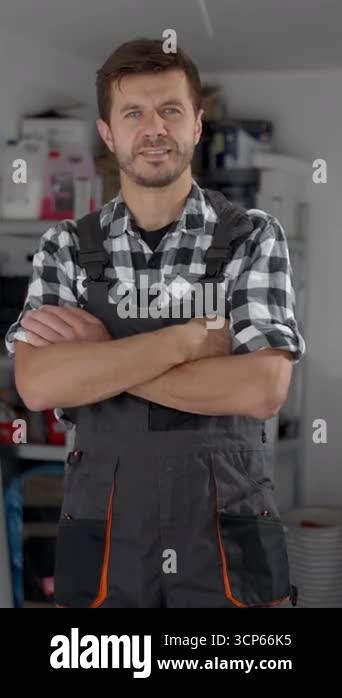 Portrait of carpenter in checkered shirt and overalls standing with ...