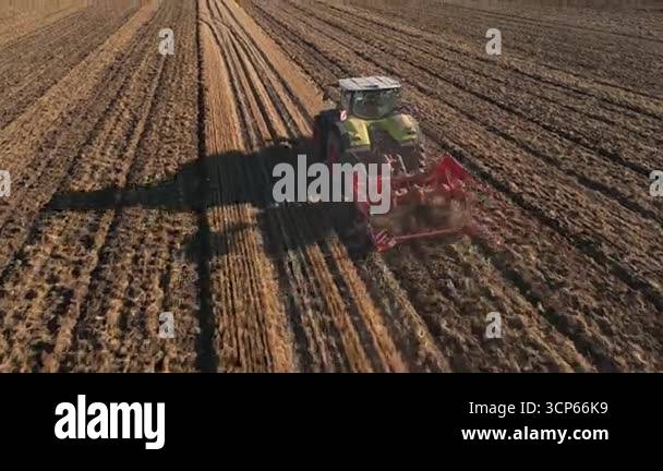Modern tractor working on farmland, cultivating soil after harvest ...