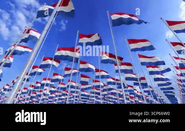 The Netherlands national flags waving against a blue sky, symbolizing ...