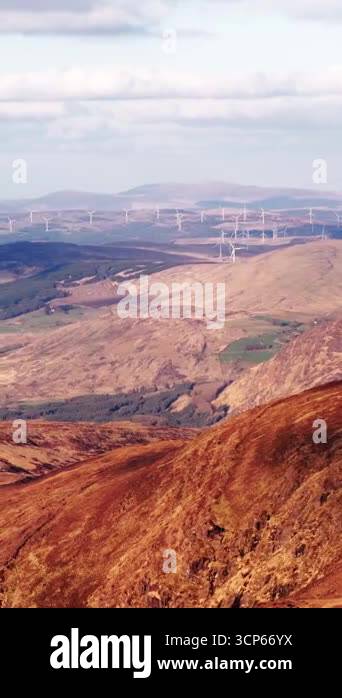 Explore the rugged beauty of the Irish countryside. Wind turbines dot the horizon, a blend of ...