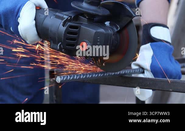 Close-up of an angle grinder cutting rebar. Female hands in work gloves ...