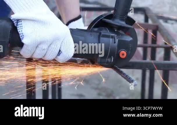 Close-up of an angle grinder cutting rebar. Female hands in work gloves ...