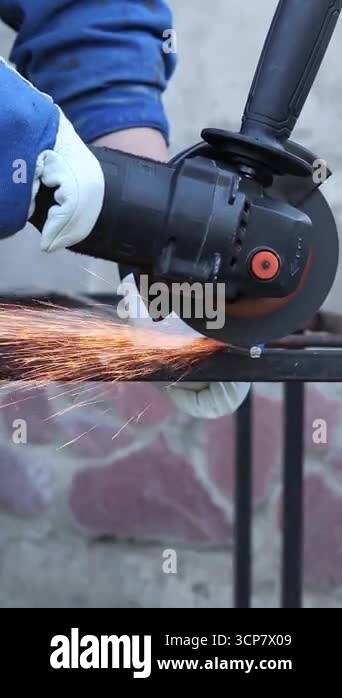 Close-up of an angle grinder cutting rebar. Female hands in work gloves ...
