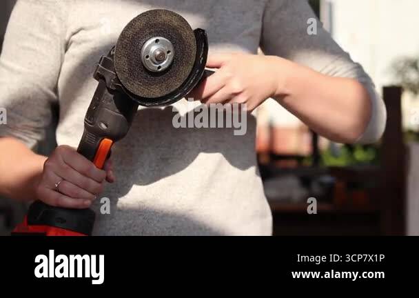 Close-up of female hands holding a cordless grinder. Woman screws a ...