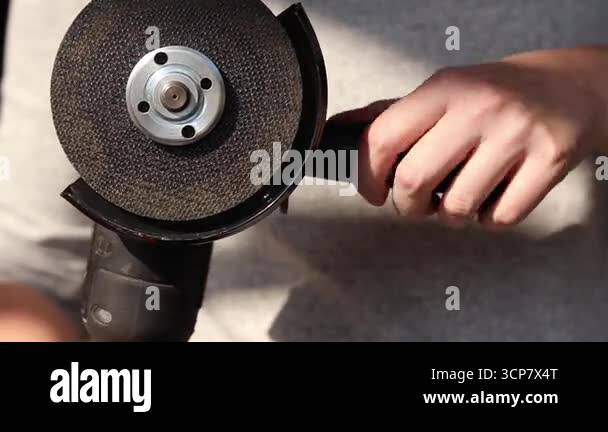 Close-up of female hands holding a cordless grinder. Woman screws a ...