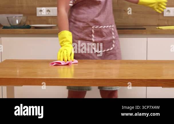 Cleaning lady wipes kitchen table. Woman in apron and yellow gloves ...