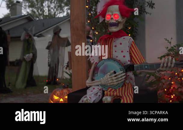 Close-up of a skeleton clown with glowing red eyes playing a banjo in a ...