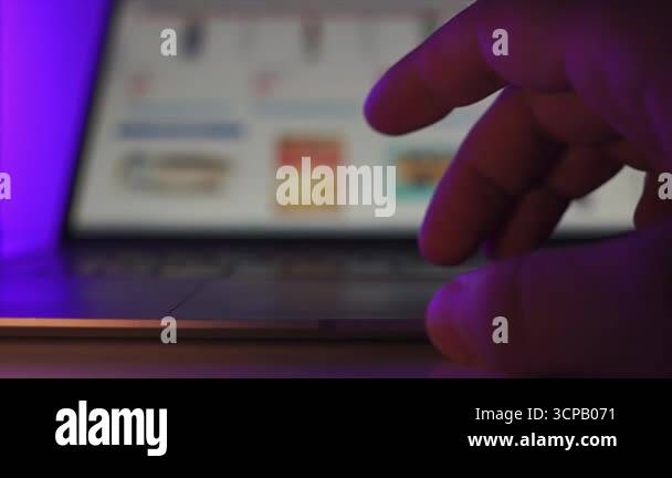 Unrecognizable male hands scrolling touchpad laptop at modern neon ...