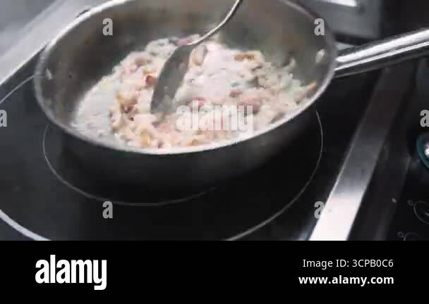 Frying meal. Stirring hot pan. Hands tossing metal saucepan on black ...
